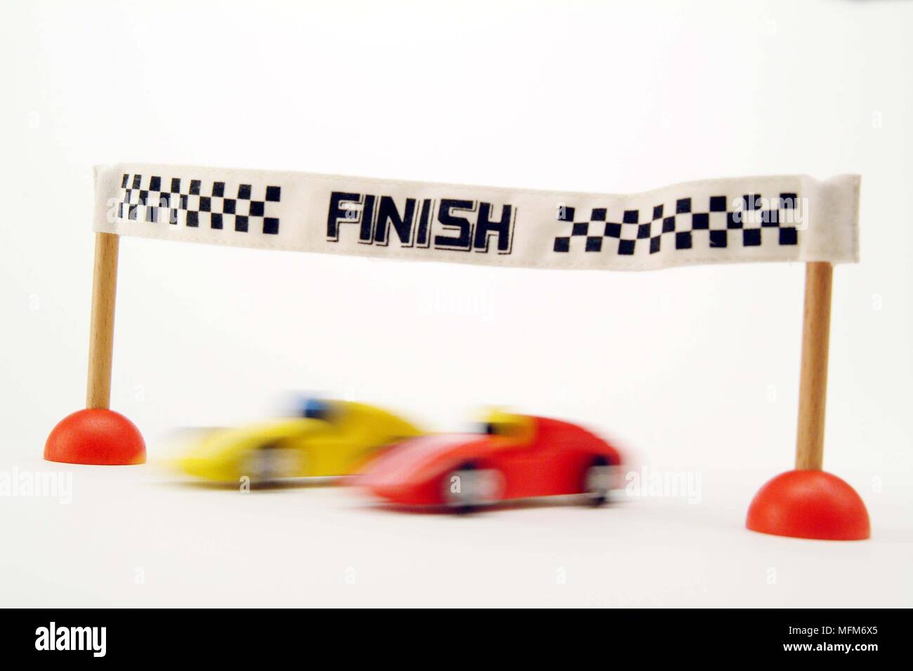 Two toy Formula One racing cars blurred as they speed under the finish ...