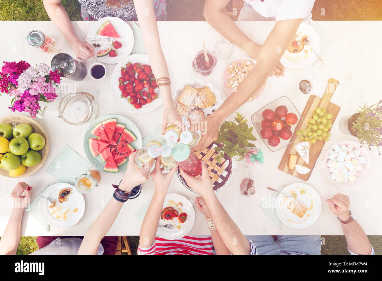 Mixed-race group eating healthy food outdoors and toasting Stock Photo ...