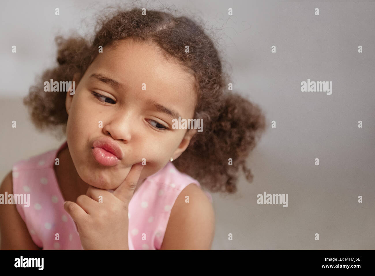 Fun confused kid girl thinking and looking serious about on pink ...