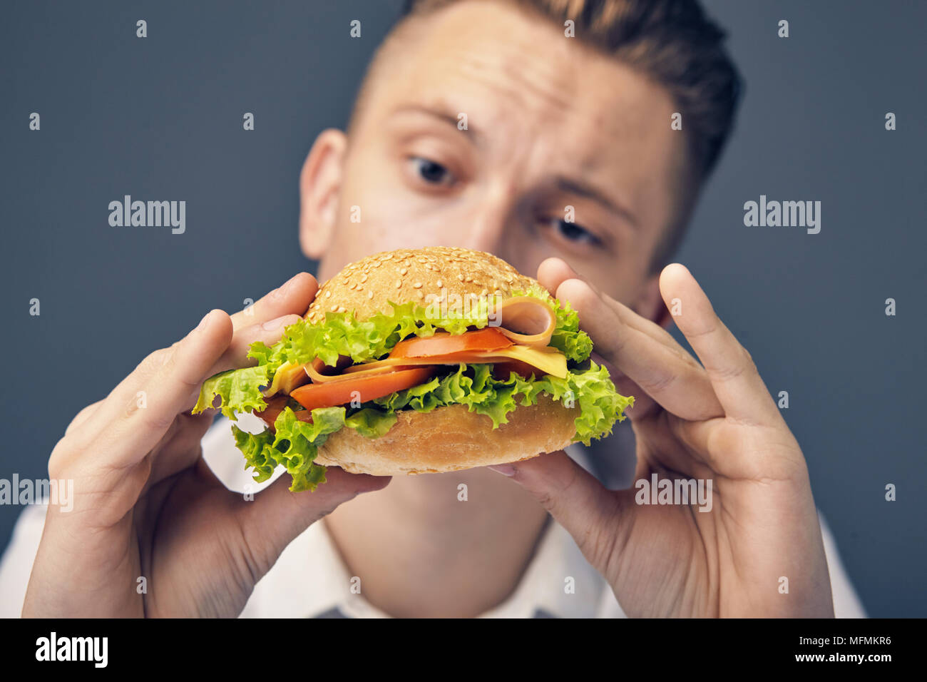 Beautiful Young man looking at a fresh burger Stock Photo - Alamy