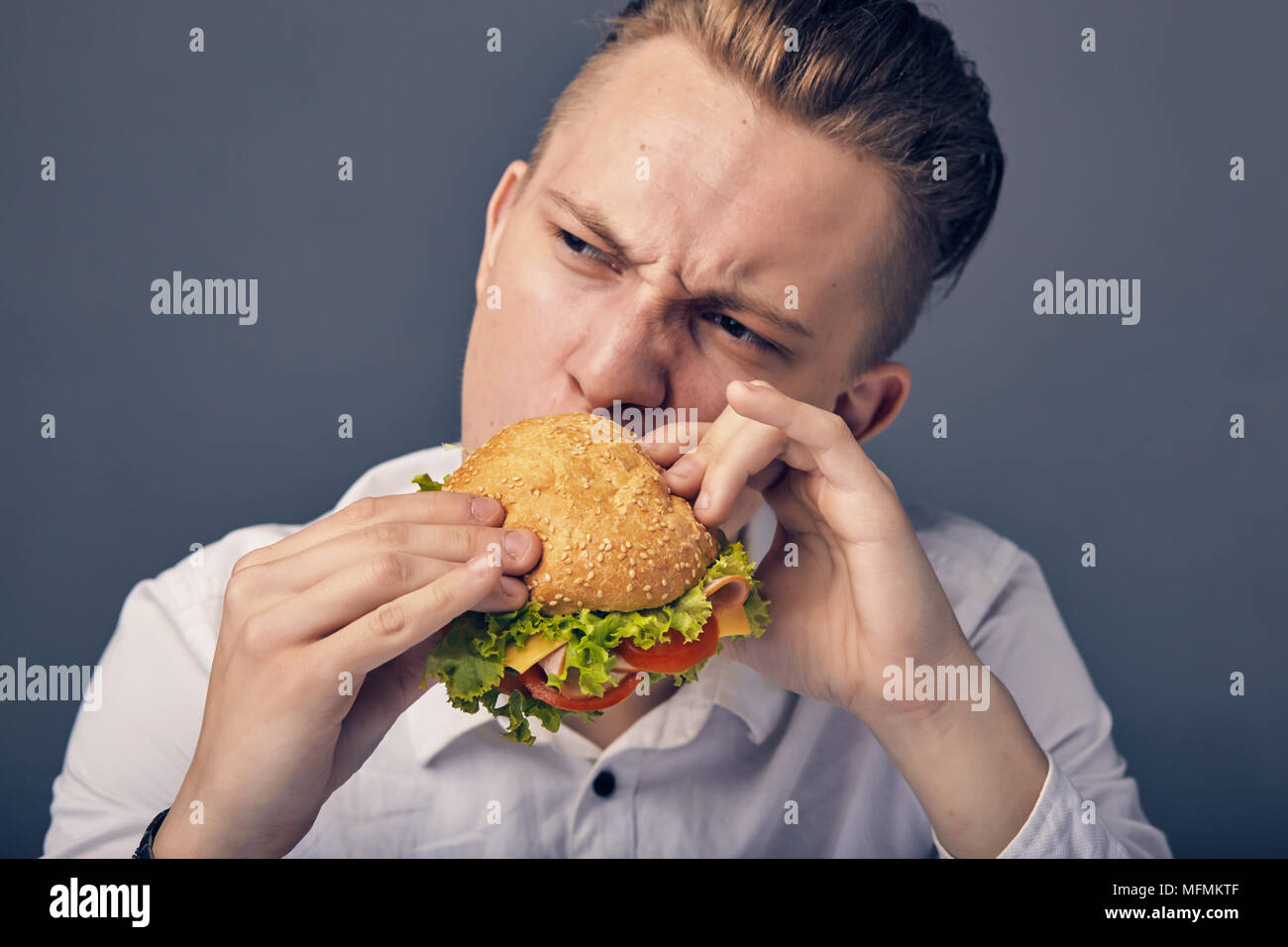 Beautiful Young man eating a fresh burger Stock Photo - Alamy