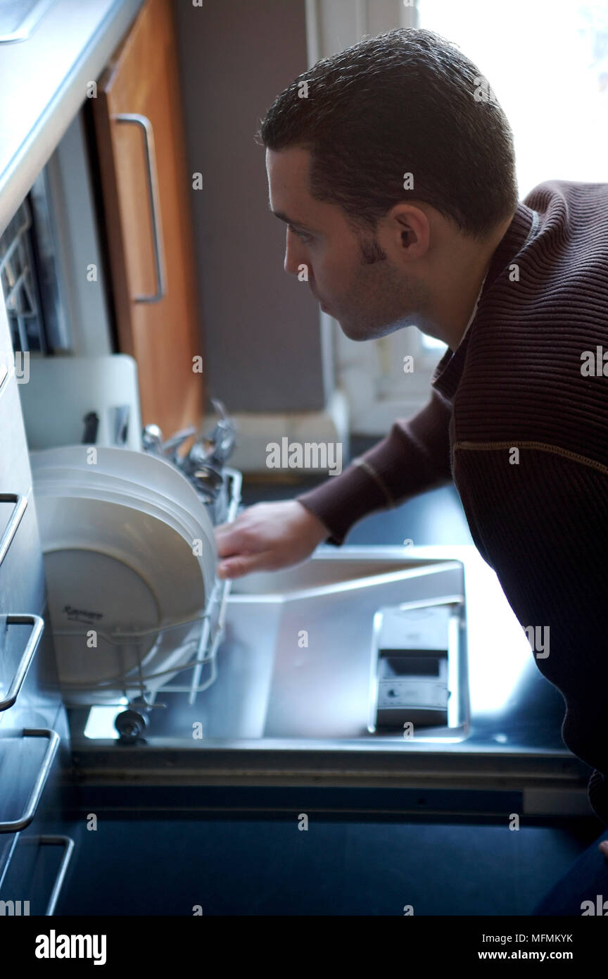 High angle view of a young man putting plates in a dish rack Ref ...