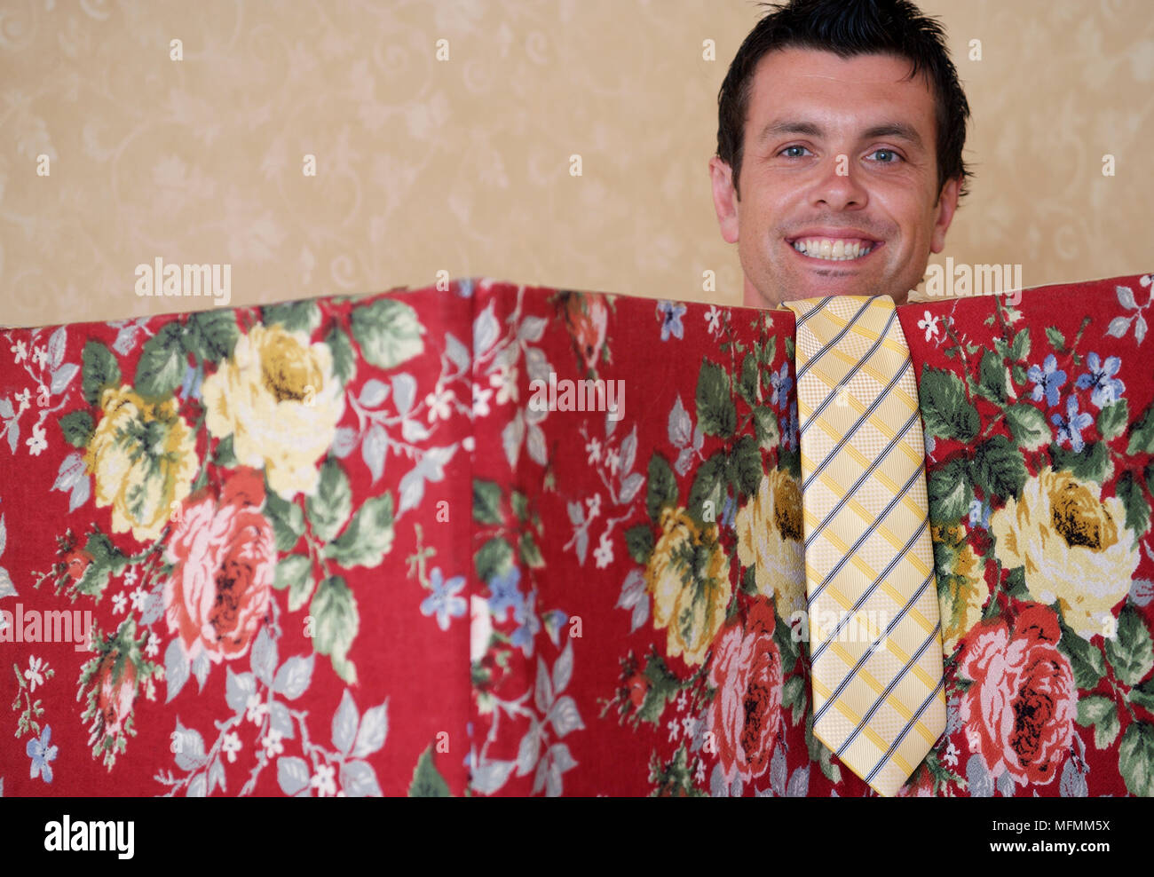 Portrait of a young man smiling and hiding behind a screen partition ...