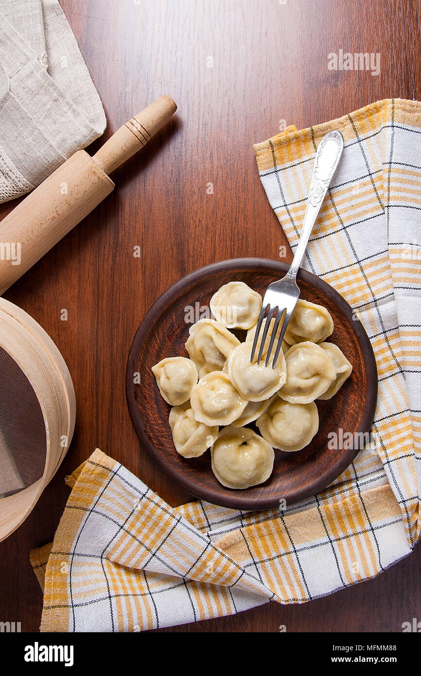 Boiled homemade meat dumplings served in clay plate with creamy sauce ...