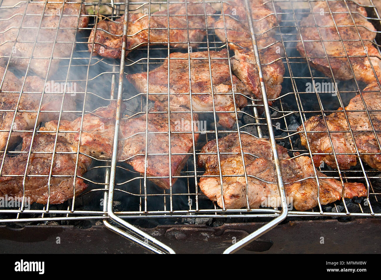 Juicy slices of meat cooking on an open flame grill. Roasted meat with ...
