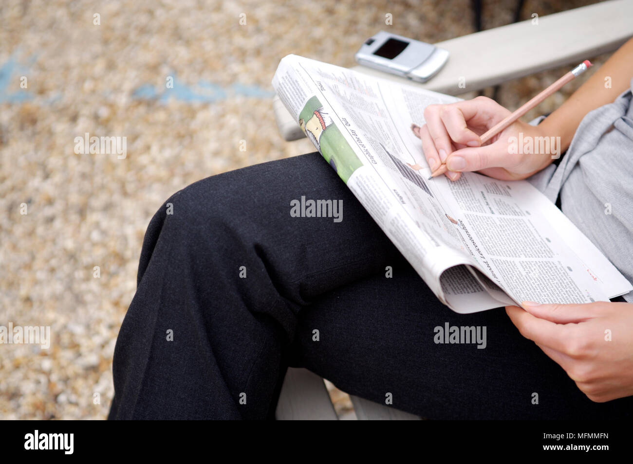 Mid section view of a woman writing with a pencil on a newspaper Ref ...