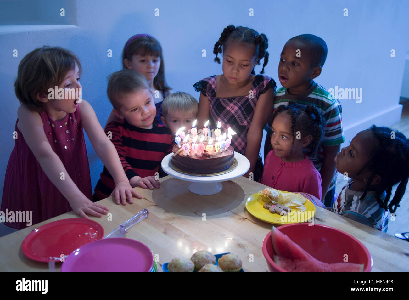 Group of children standing in front of a birthday cake at a birthday ...