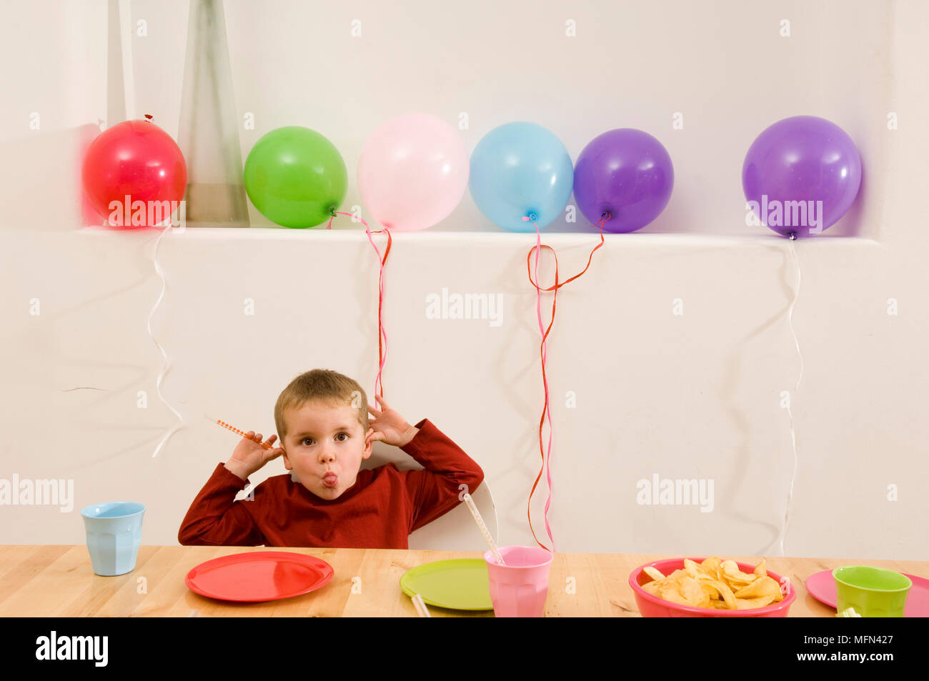 Portrait of a boy sitting at a table and making a face Ref: Compulsory ...