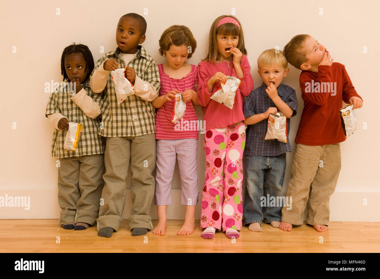 Three girls standing with three boys eating crisps Ref: Compulsory ...