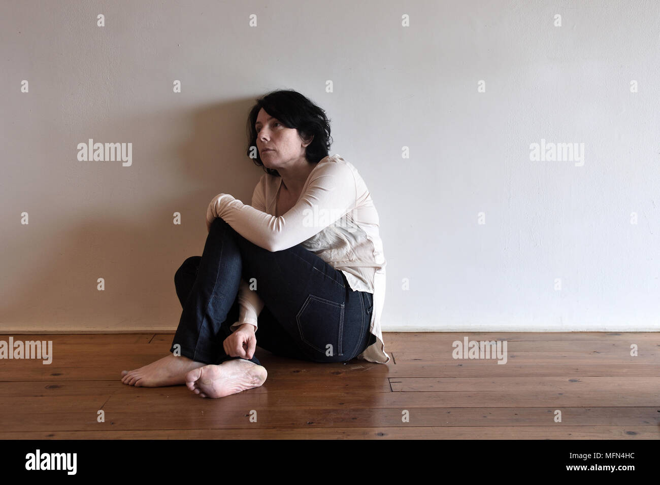 a sad woman on the floor of her house Stock Photo - Alamy