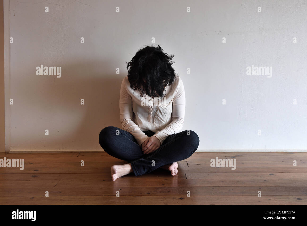 a sad woman on the floor of her house Stock Photo - Alamy