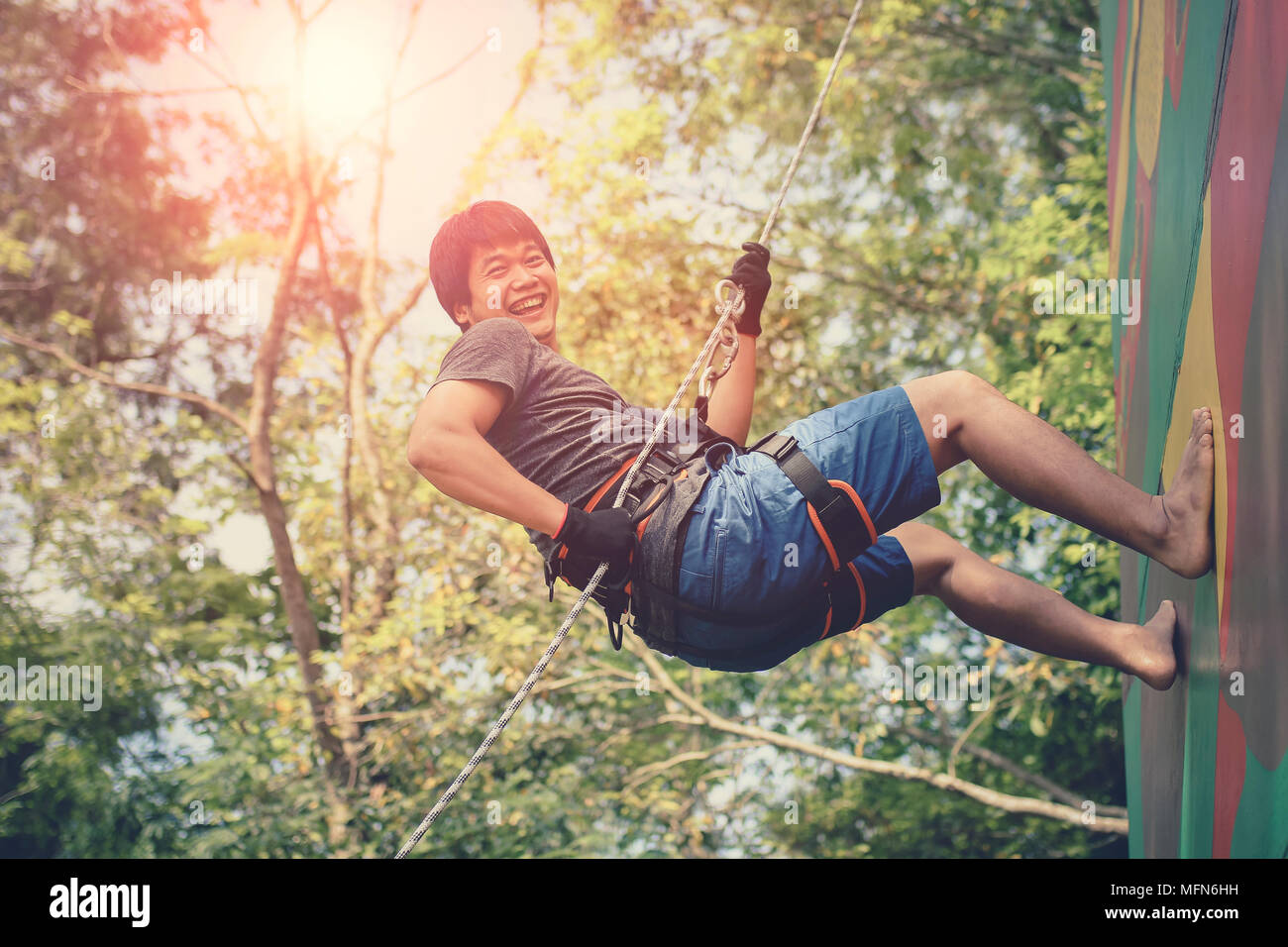 asian younger man hanging on clip hiking safety rope and laughing with ...