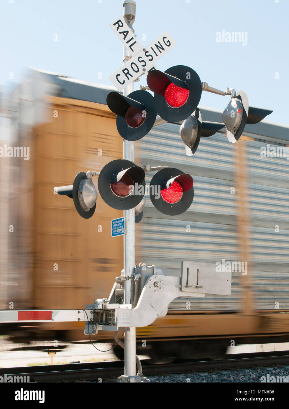 Train speeding by train crossing sign Stock Photo - Alamy