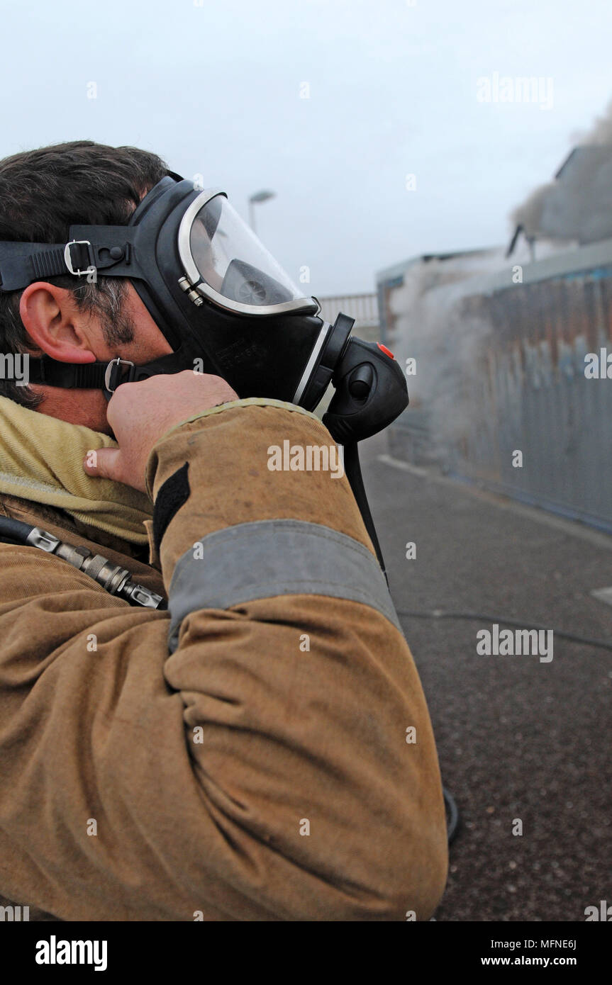 Fireman on a fire training ground donning breathing apparatus for an ...