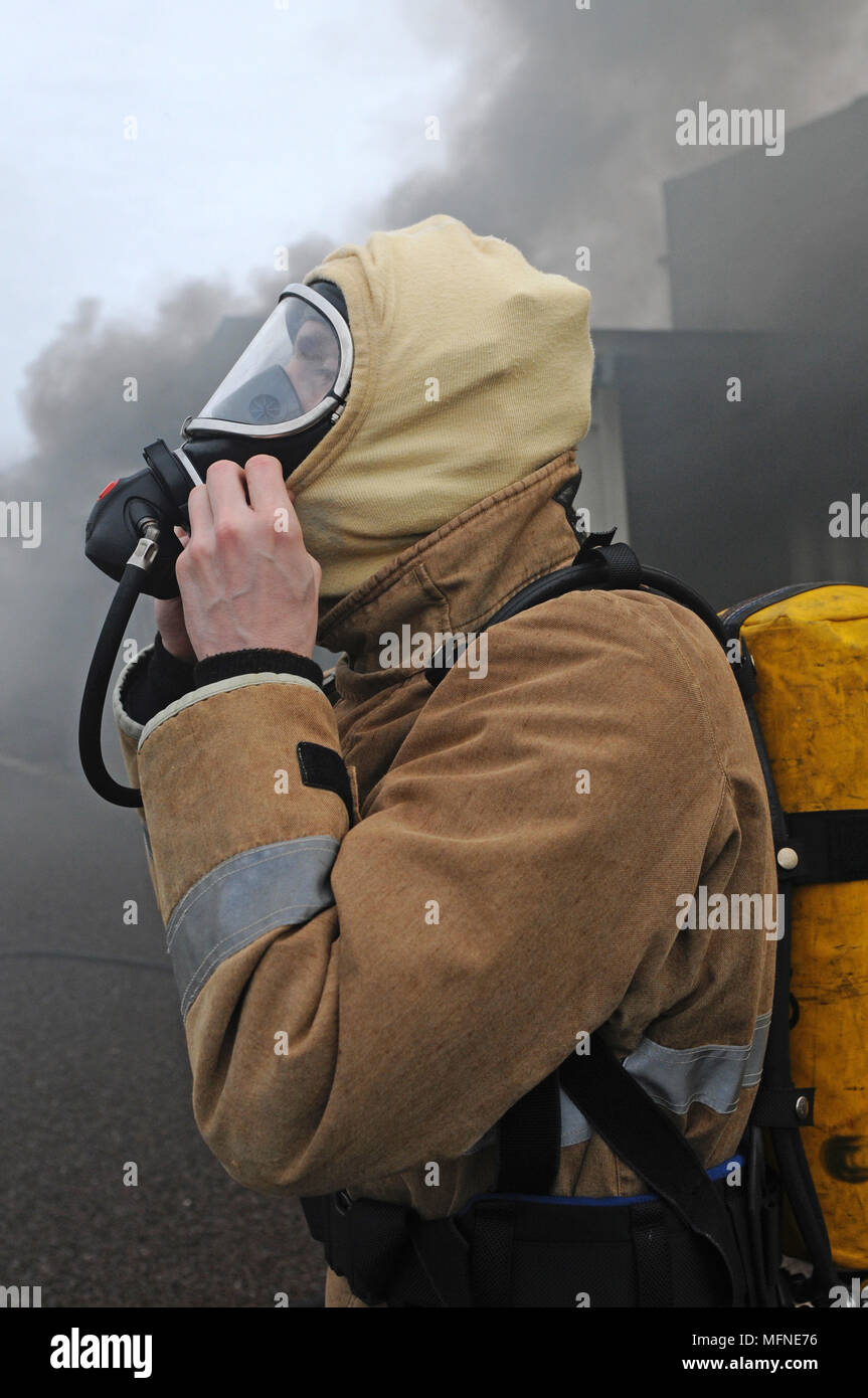 Fireman on a fire training ground donning breathing apparatus for an ...