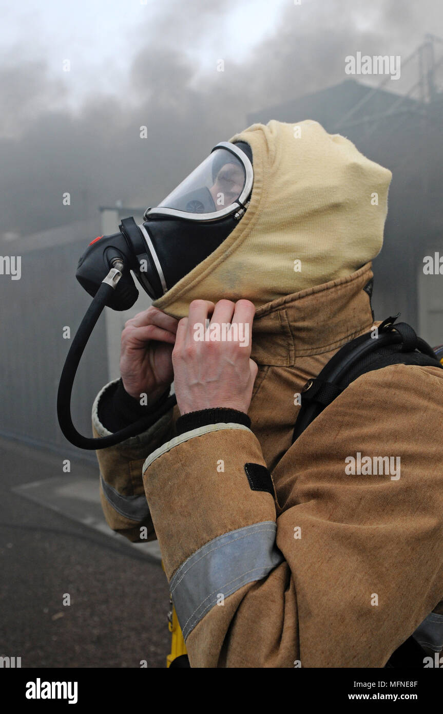 Fireman on a fire training ground donning breathing apparatus for an ...