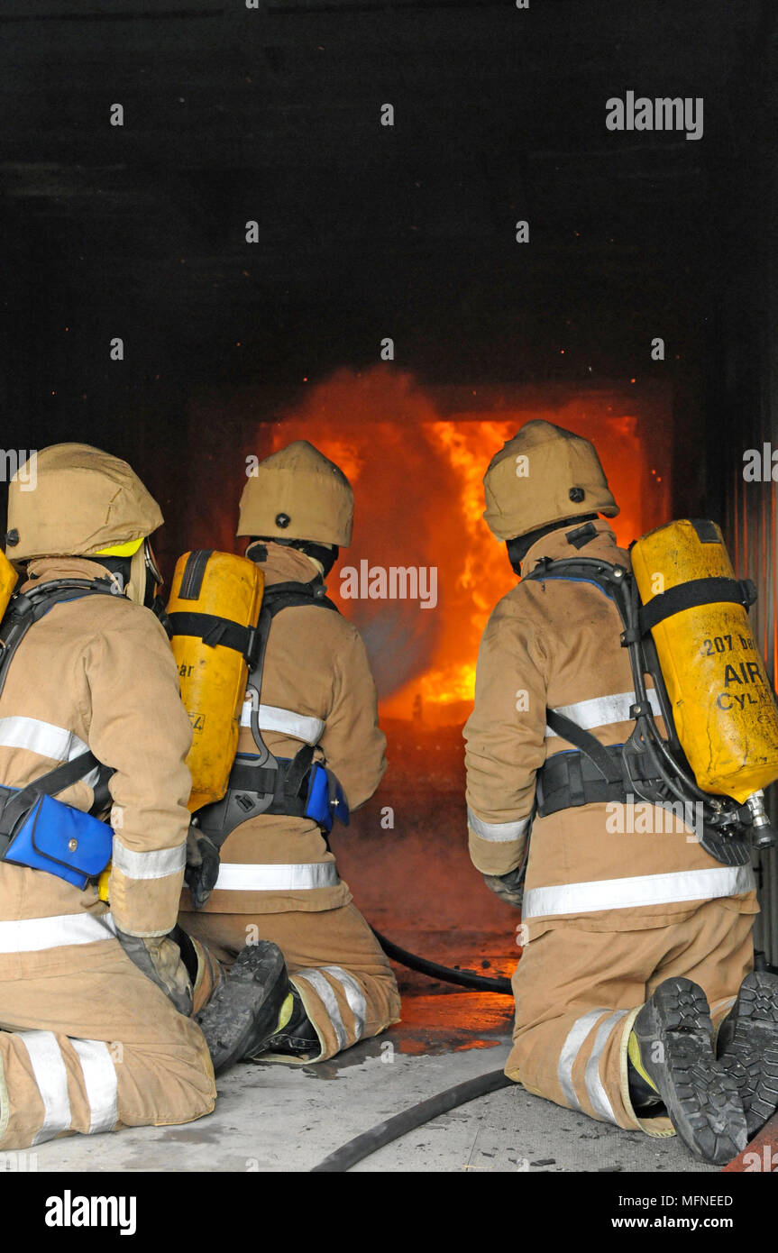 Fireman on a fire training ground donning breathing apparatus for an ...