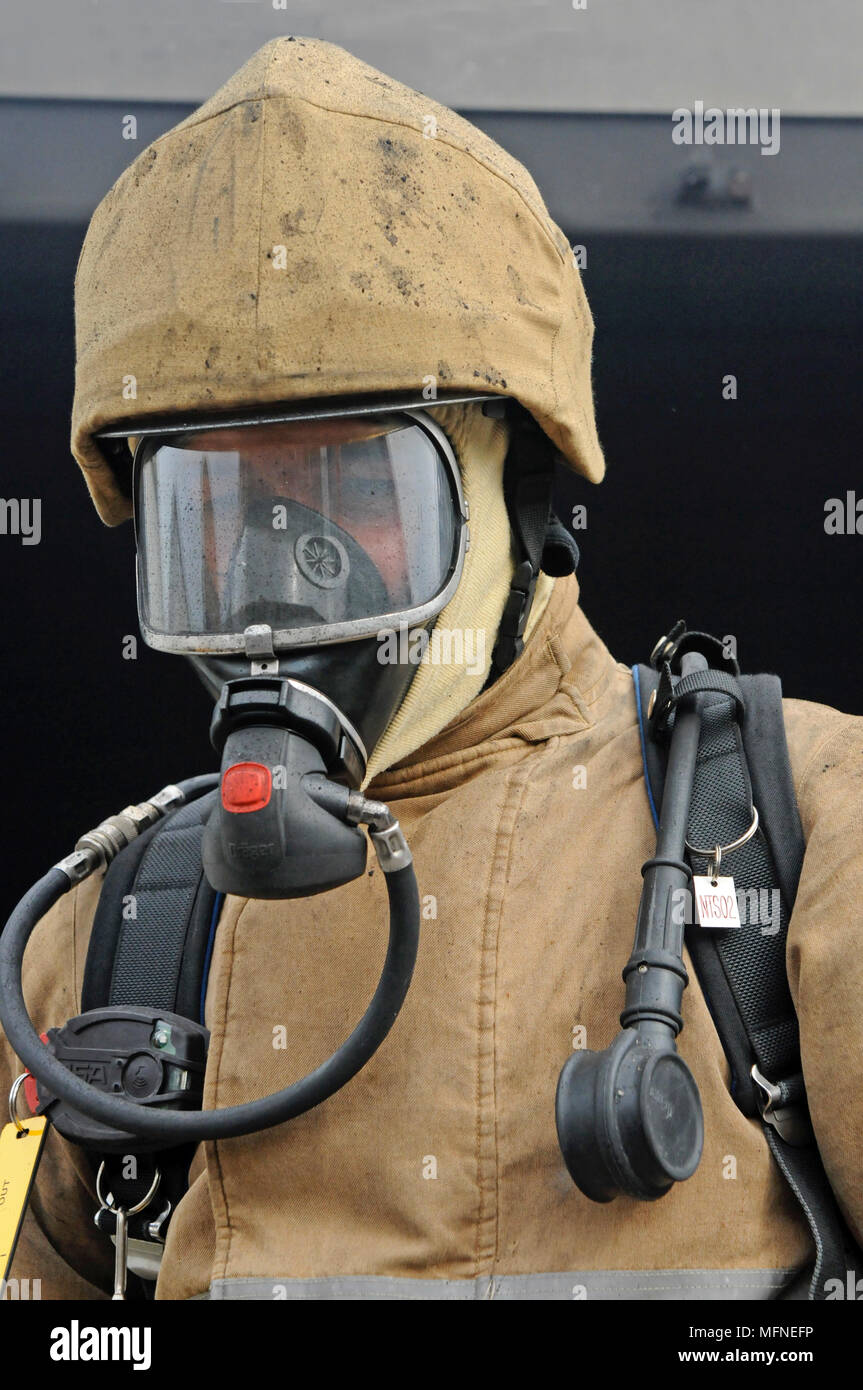 Fireman on a fire training ground donning breathing apparatus for an ...