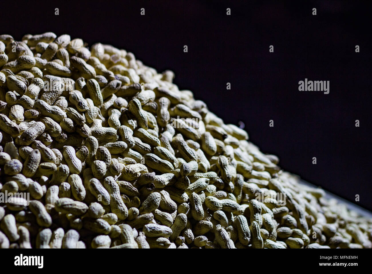 ground nuts in a heap for sale against black background. peanut with ...