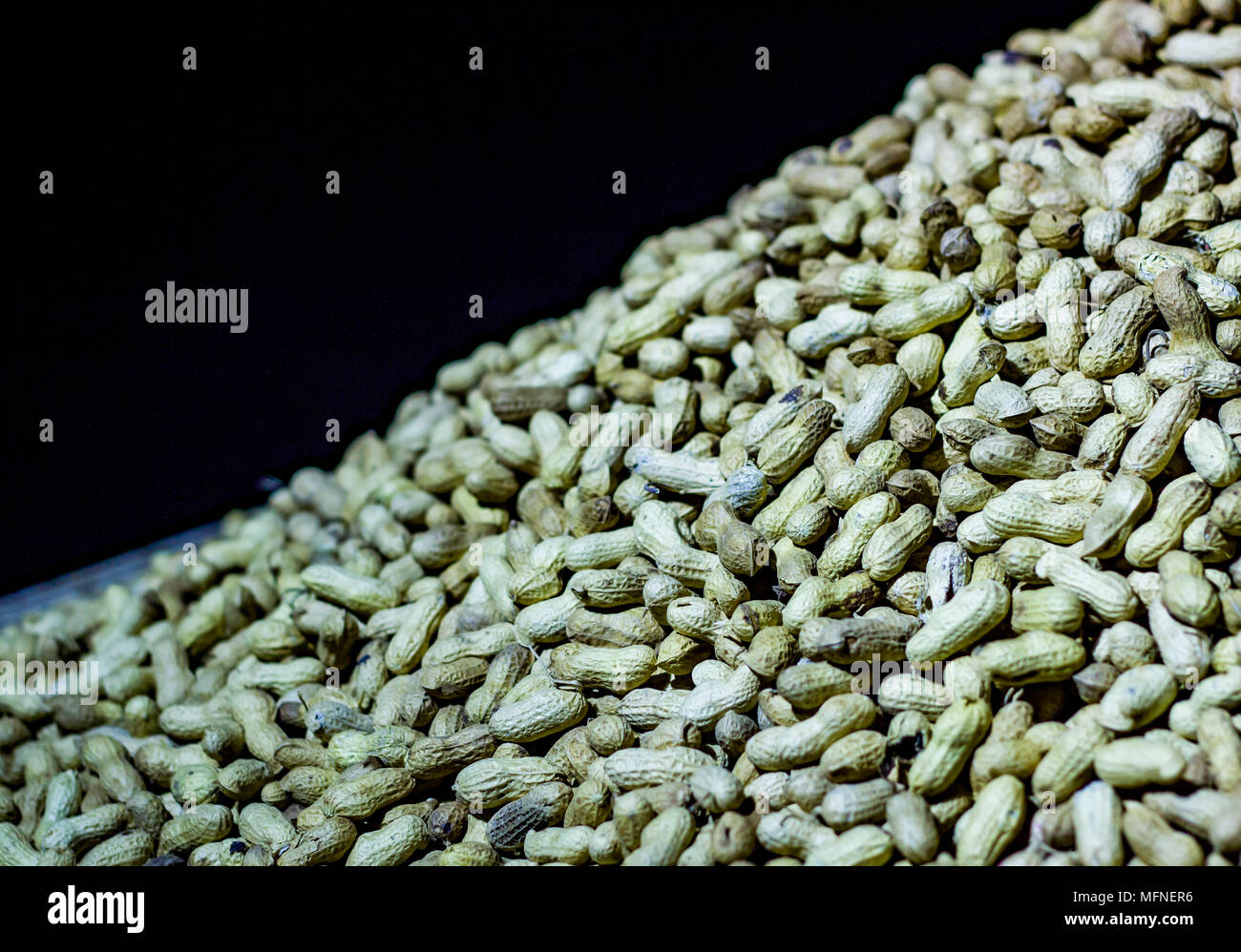 ground nuts in a heap for sale against black background. peanut with ...
