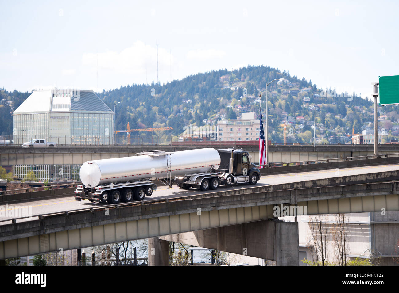 Big rig black semi truck transporting fuel in long round stainless ...