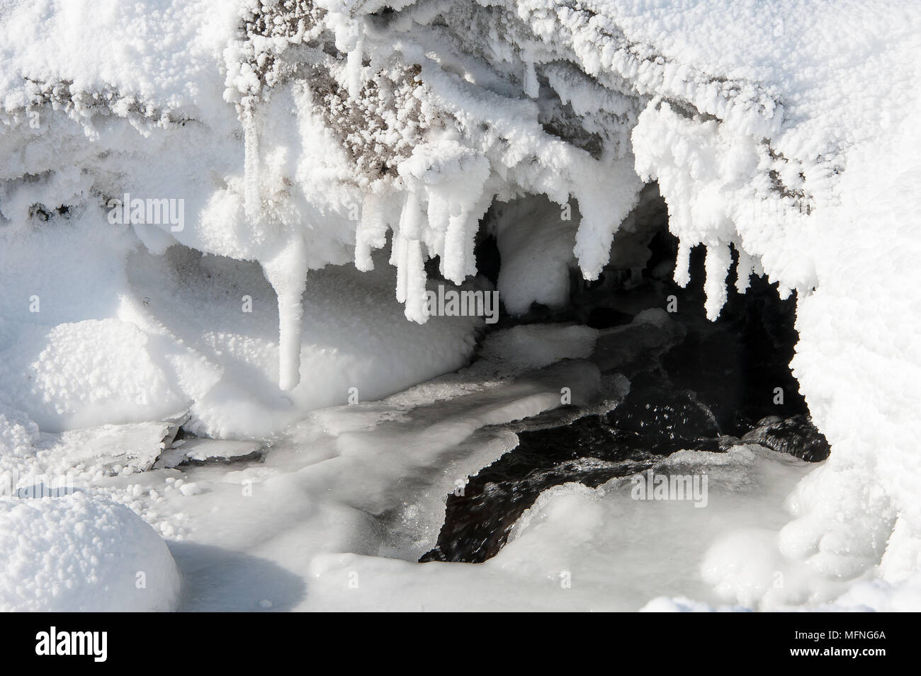 Icicles form on natural rock bridge to black flowing water - Godafoss ...