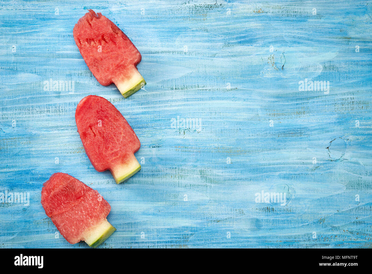 Watermelon peaces cut in ice cream lolly pop shape on bright blue ...