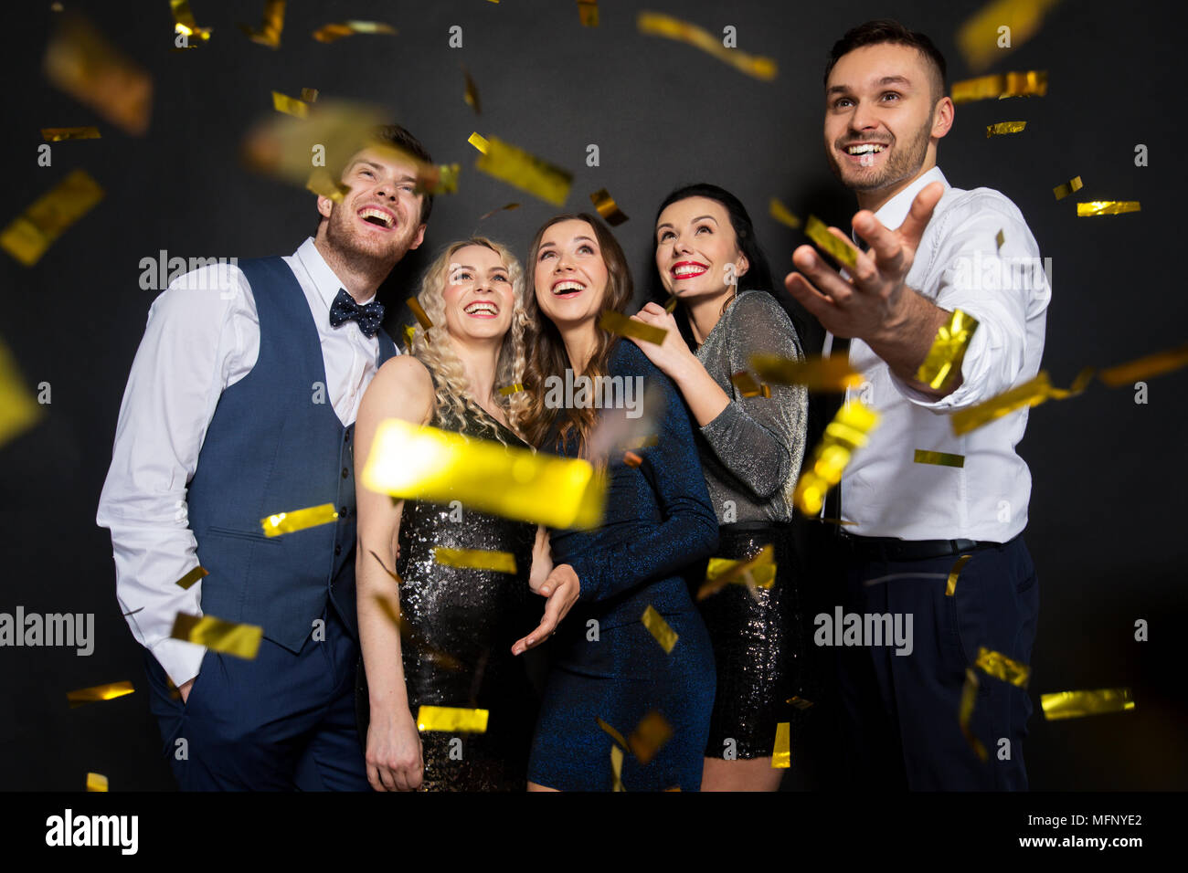 happy friends at party under confetti over black Stock Photo - Alamy
