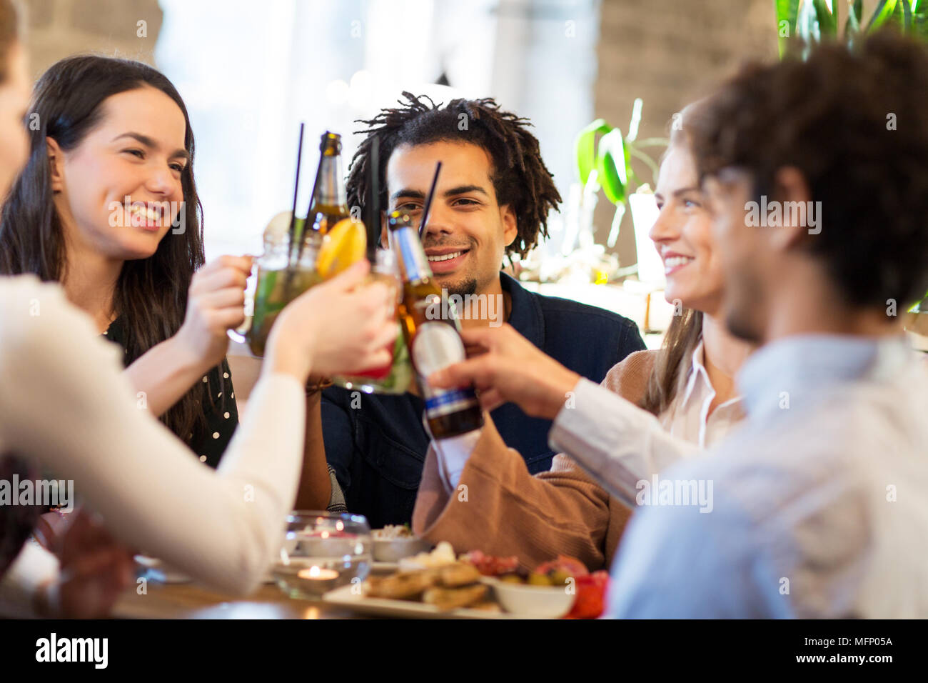 happy friends clinking drinks at bar Stock Photo - Alamy