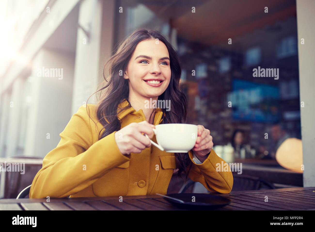 happy woman drinking cocoa at city street cafe Stock Photo - Alamy
