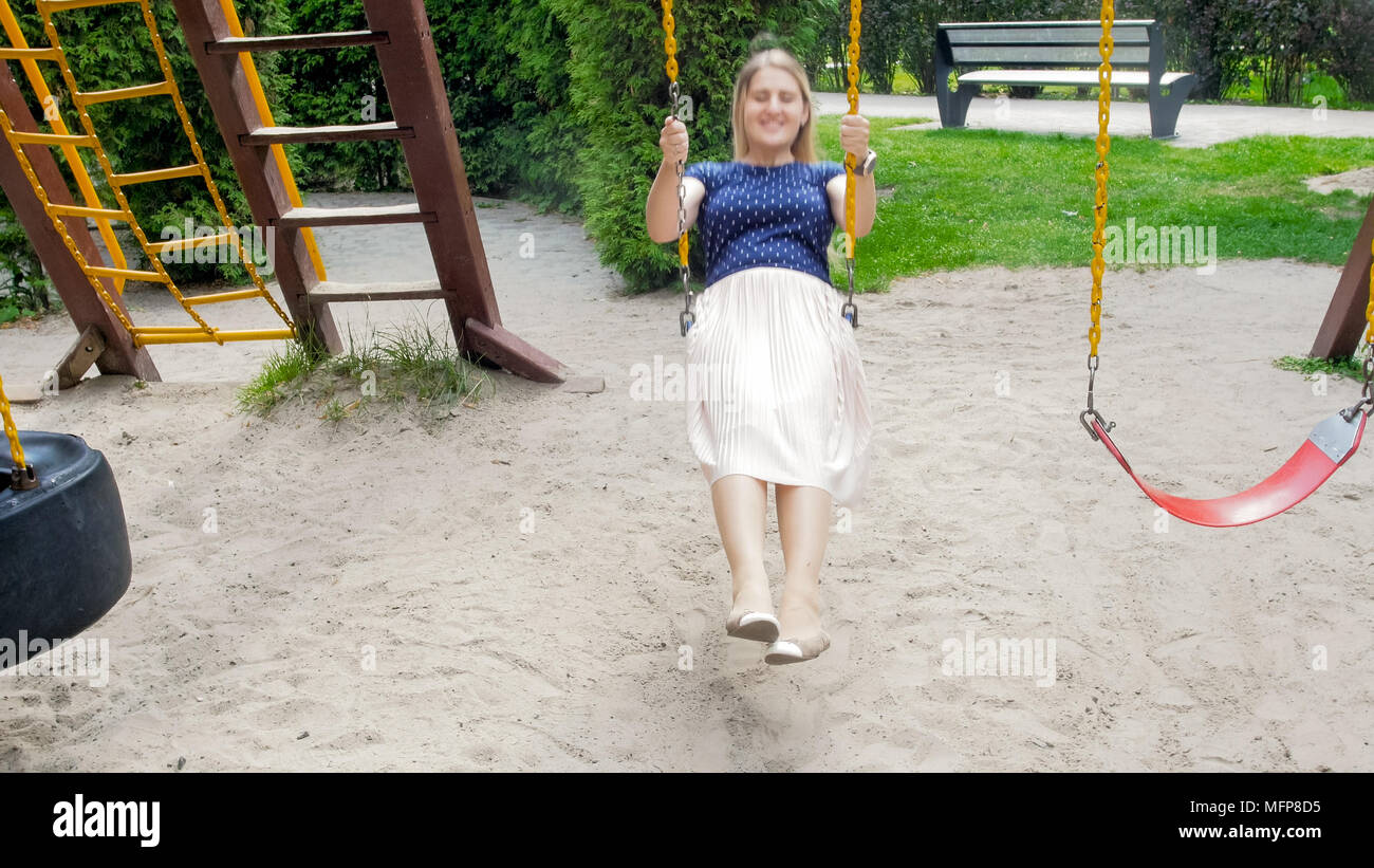 Beautiful young woman swinging on children playground Stock Photo - Alamy