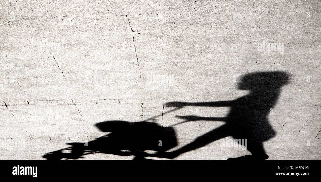 Shadow silhouette of a young woman pushing a baby stroller on city ...