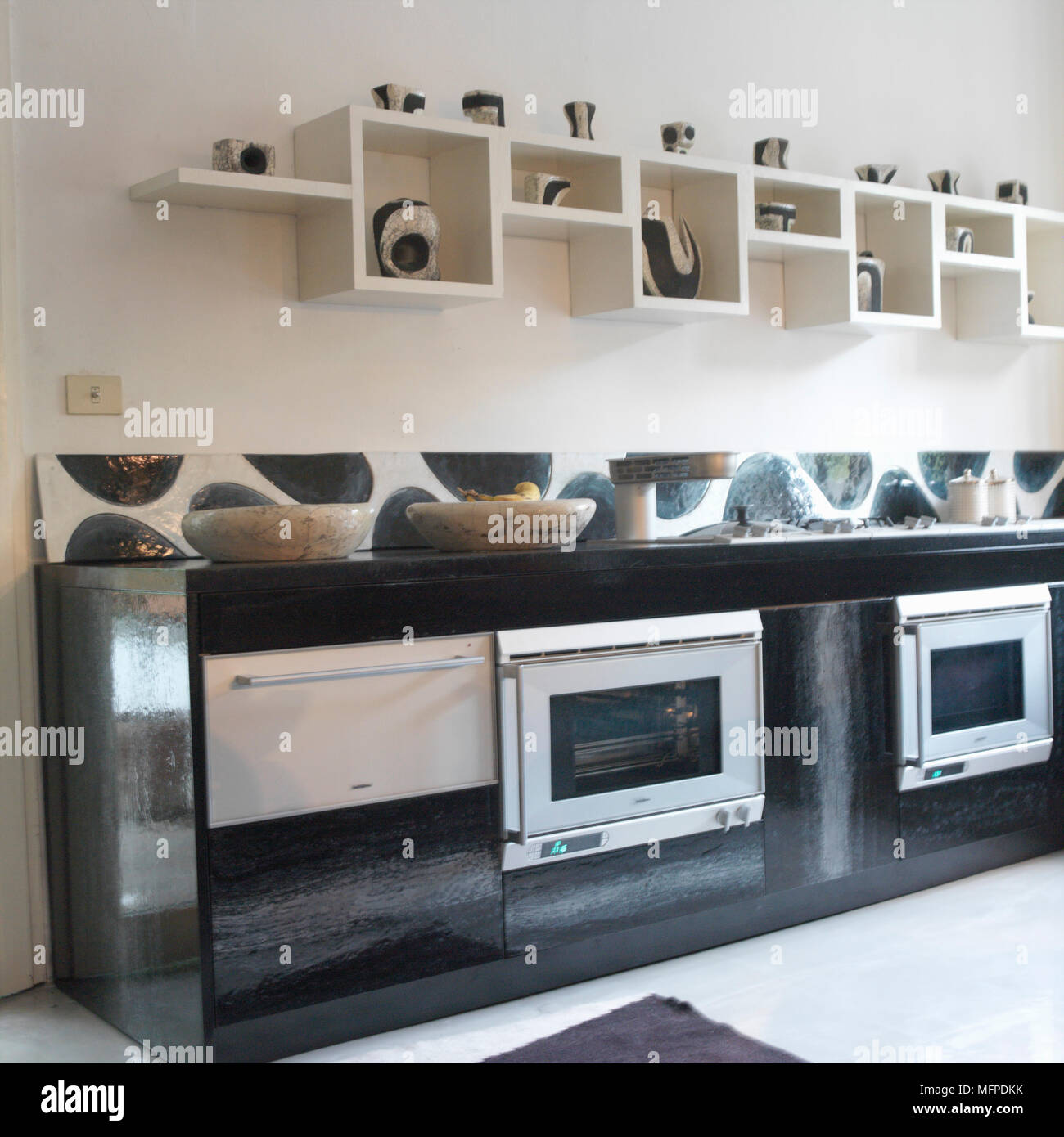 A modern kitchen, black units with integral ovens, storage boxes ...