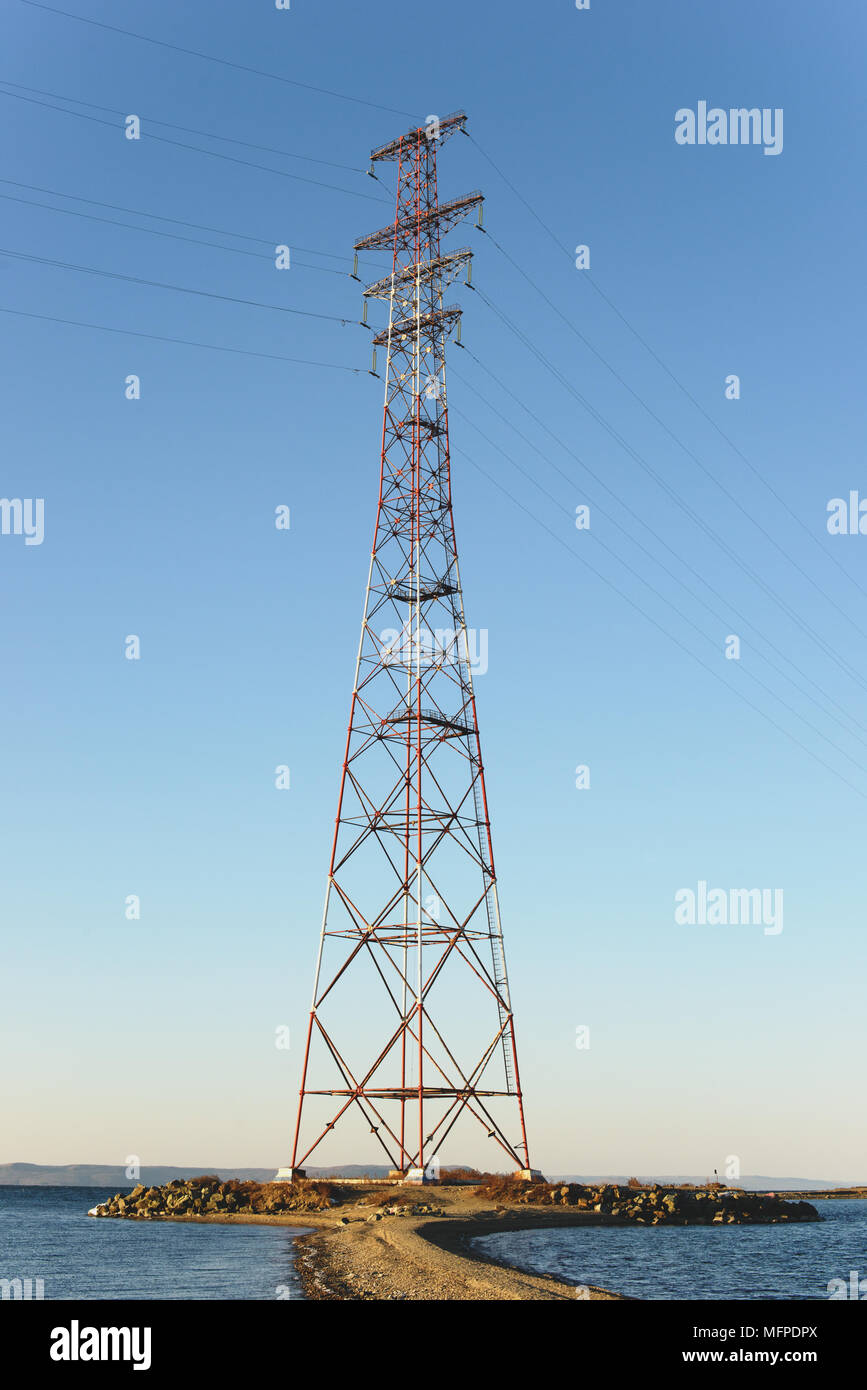 Pylon and transmission power line on the sea coast in front of sky ...