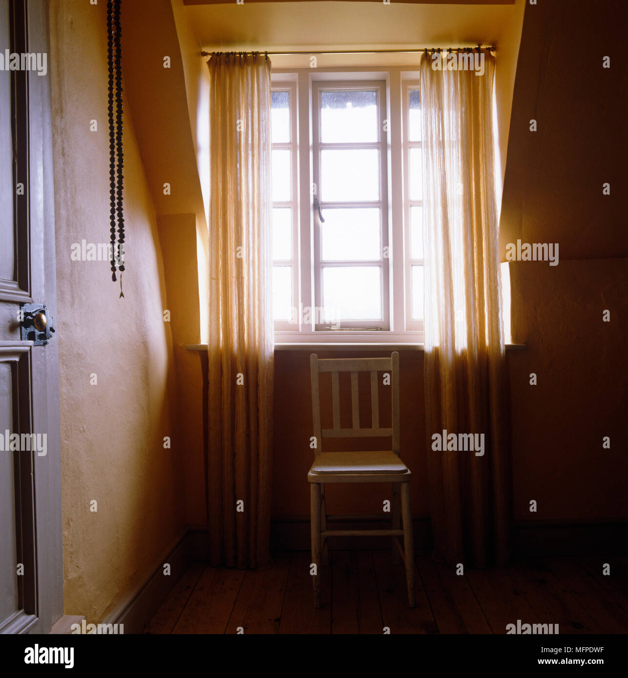 Simple chair below window Stock Photo - Alamy