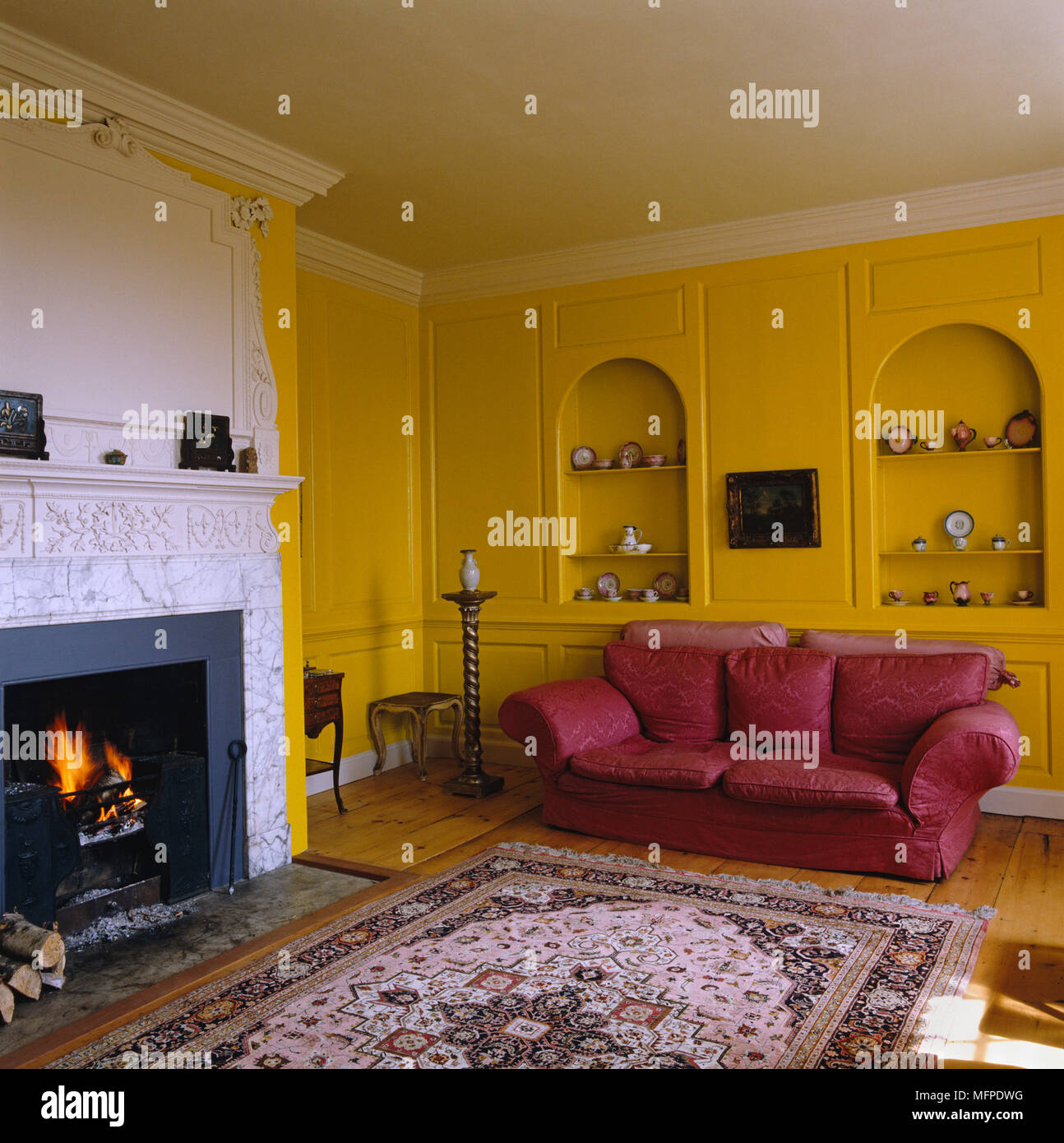 Upholstered raspberry red sofa in front of yellow wall with alcoves ...