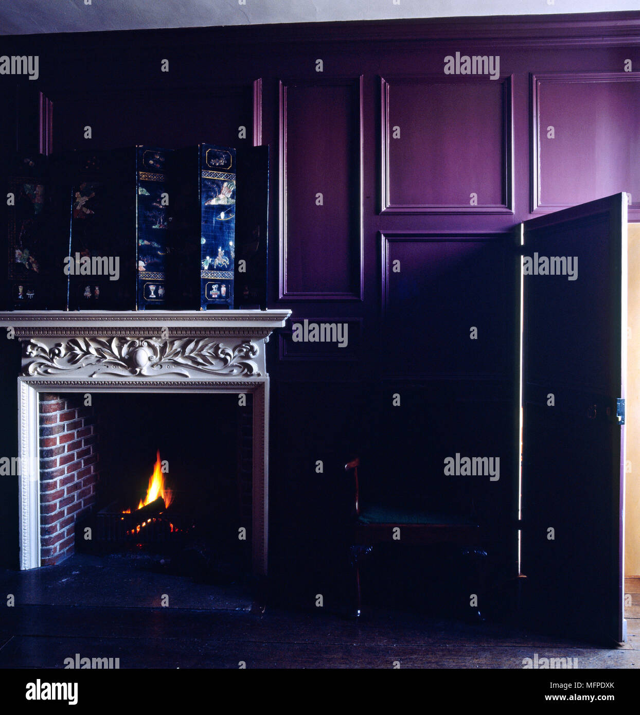 Period style fireplace with lit fire in purple panelled room Stock ...