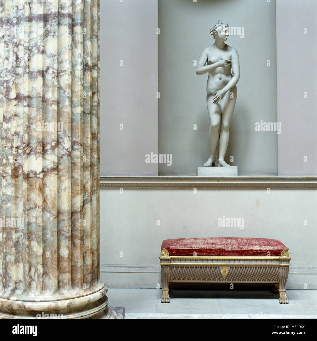 Classical style statue in alcove above seat with red leather seating ...