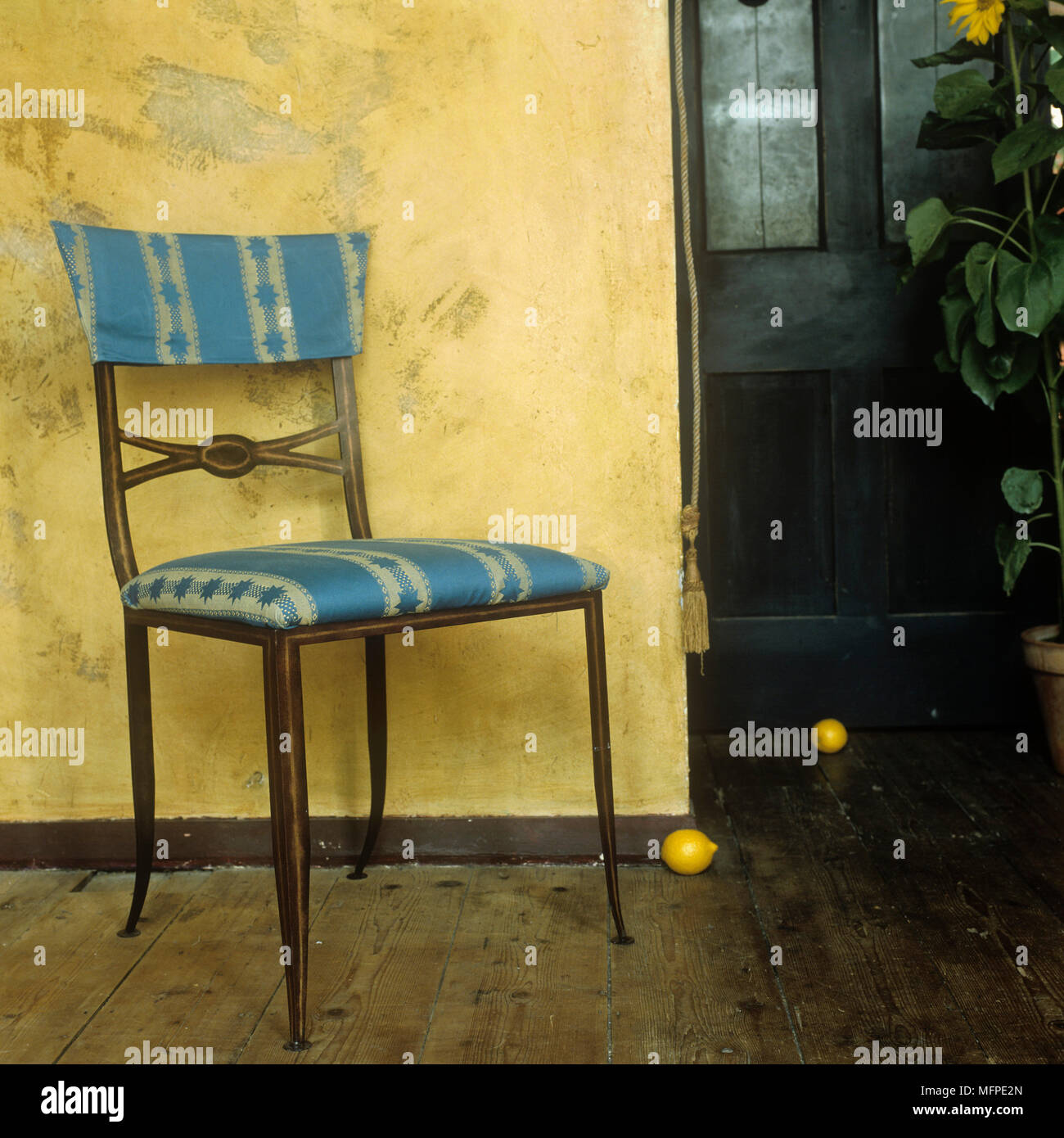 Wooden chair with blue and yellow fabric against yellow wall Stock ...