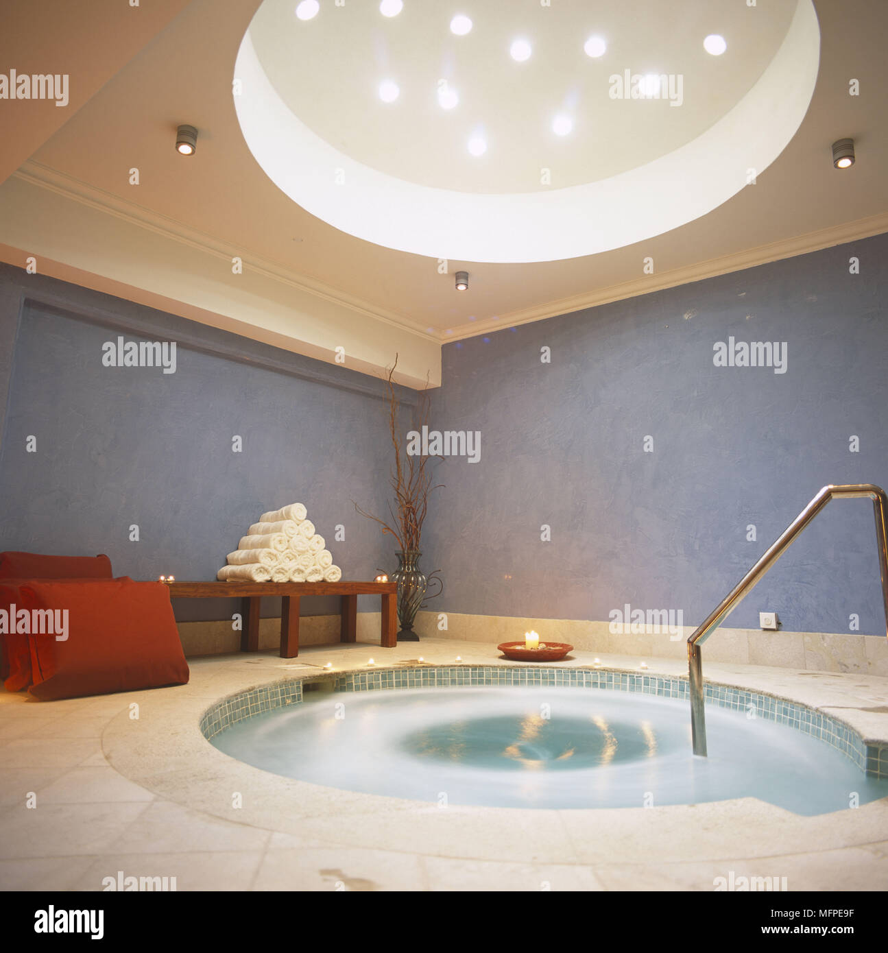 An indoor pool surrounded by candles and rolled up towels with a ...