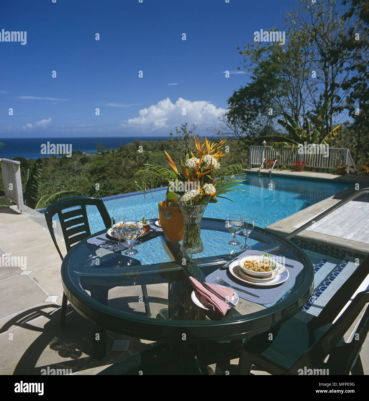 An outdoor dining table with two place setting a deck area and an ...