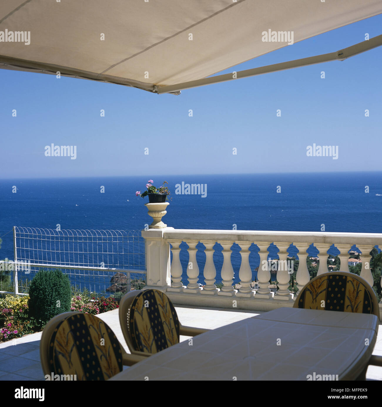 The view of a blue ocean from a veranda with an awing above a table and ...
