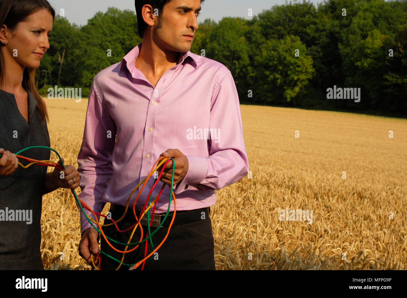 Young man and a young woman standing in a field and holding power ...