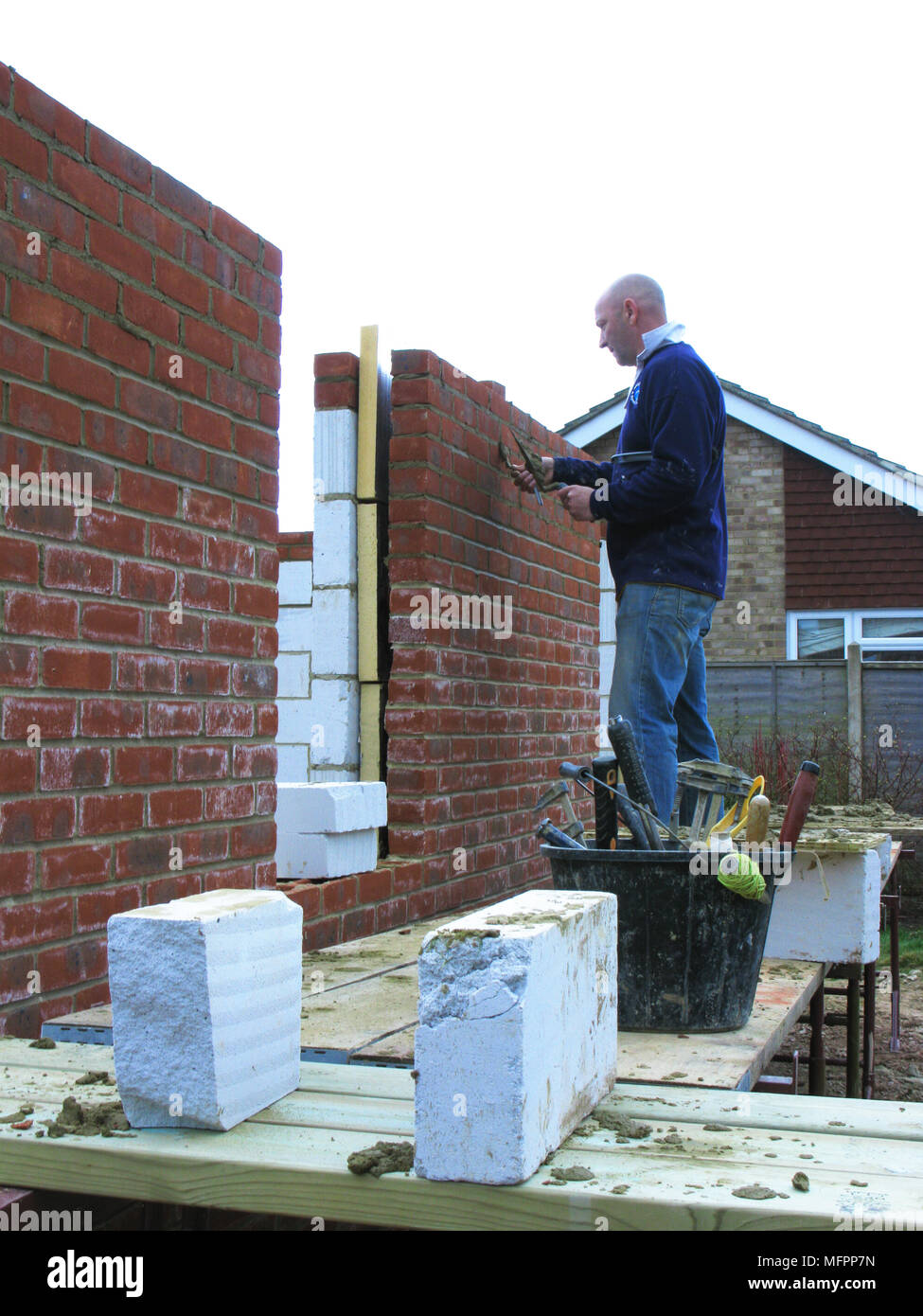 Builder / construction worker building a brick wall cementing bricks in ...