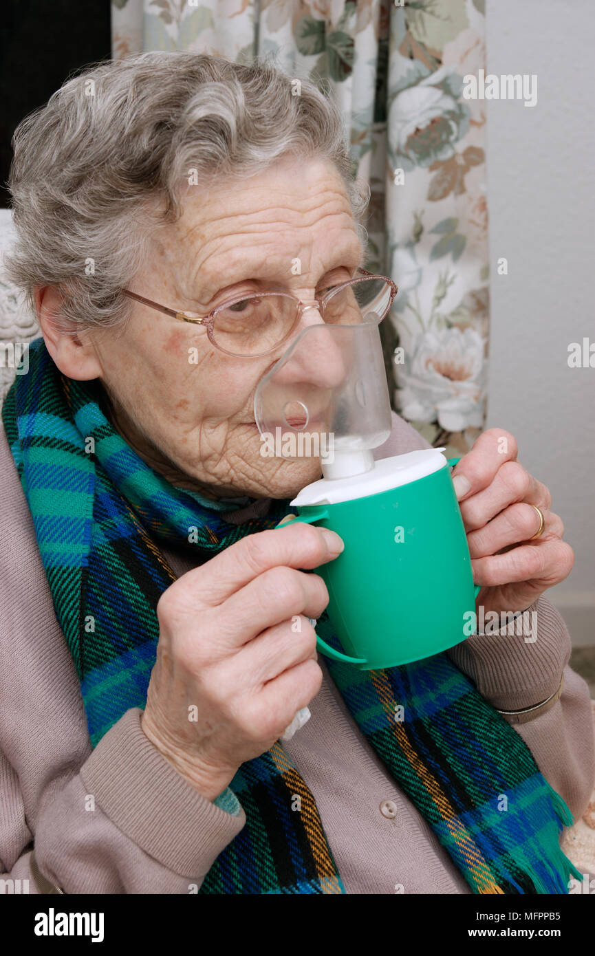 Elderly woman using a steam inhaler inhaling a decongestant for colds ...