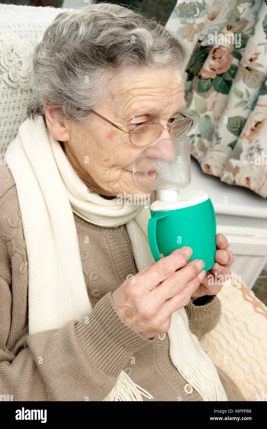 Elderly woman using a steam inhaler inhaling a decongestant for colds ...