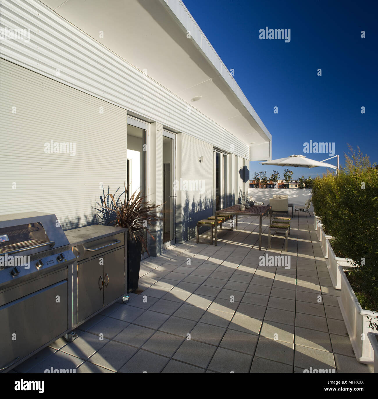 Exterior of modern house with paved terrace area with table and chairs ...