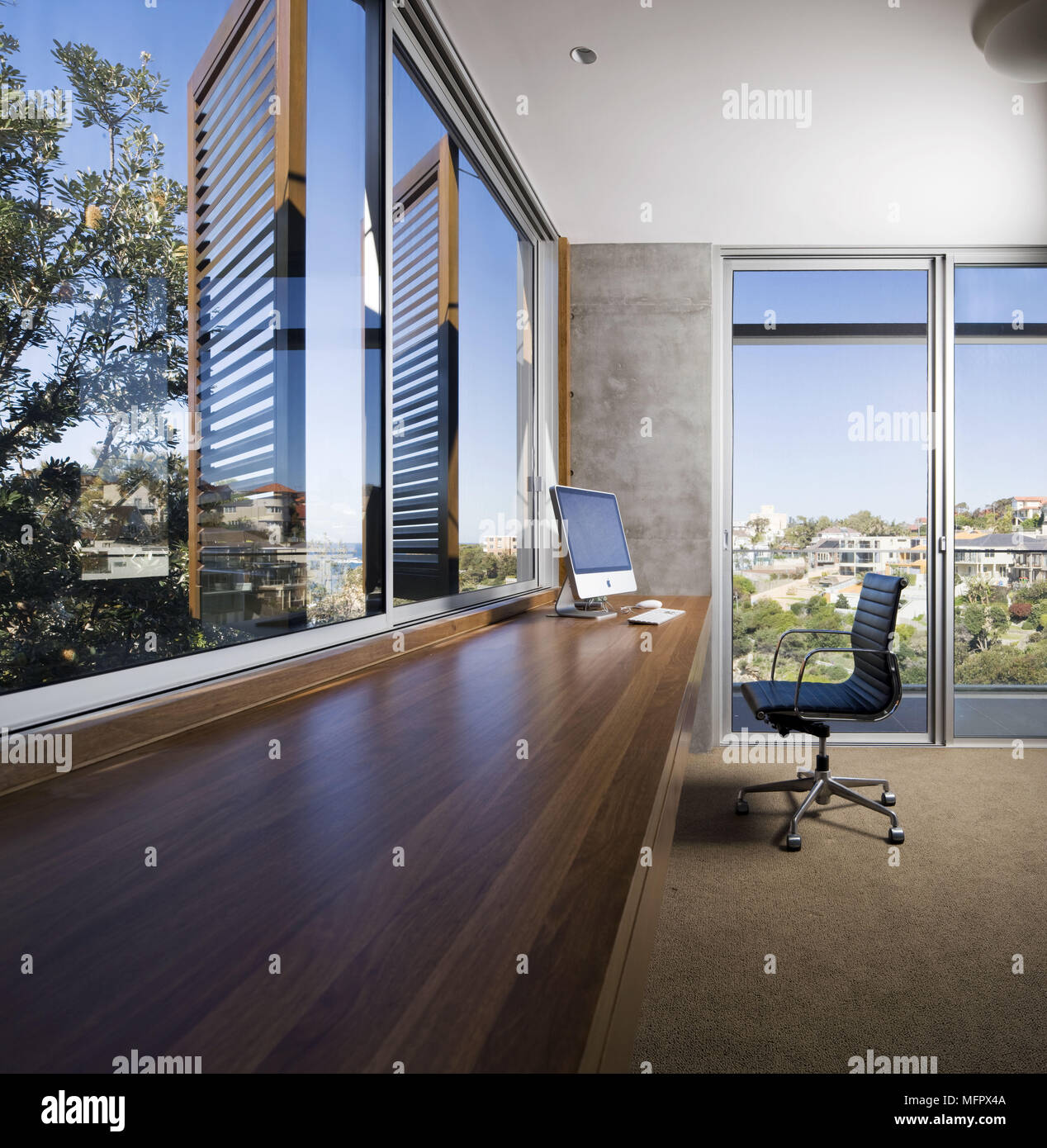 Leather swivel chair at computer on built in table shelf in modern home ...