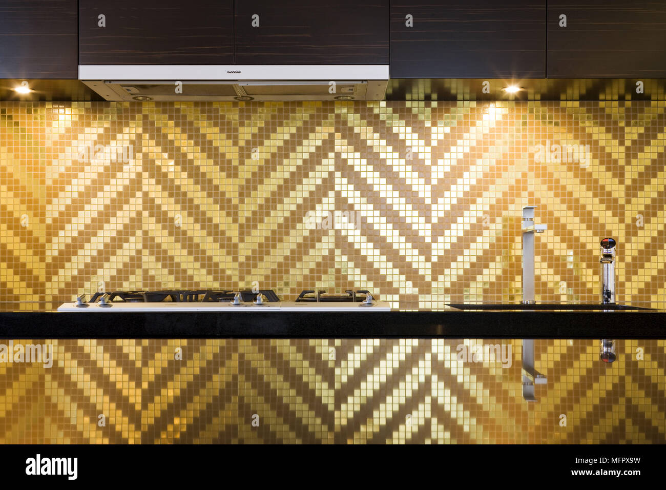 Sink tap fitting and hob set in unit in modern kitchen with patterned ...