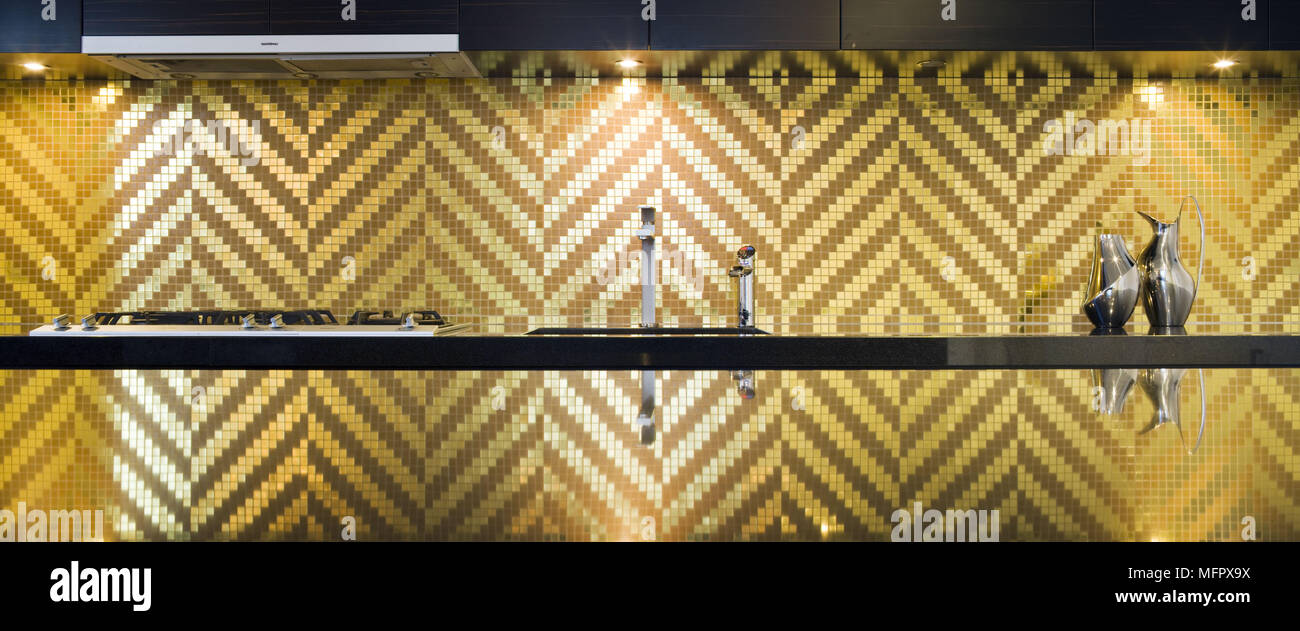 Sink tap fitting and hob set in unit in modern kitchen with patterned ...